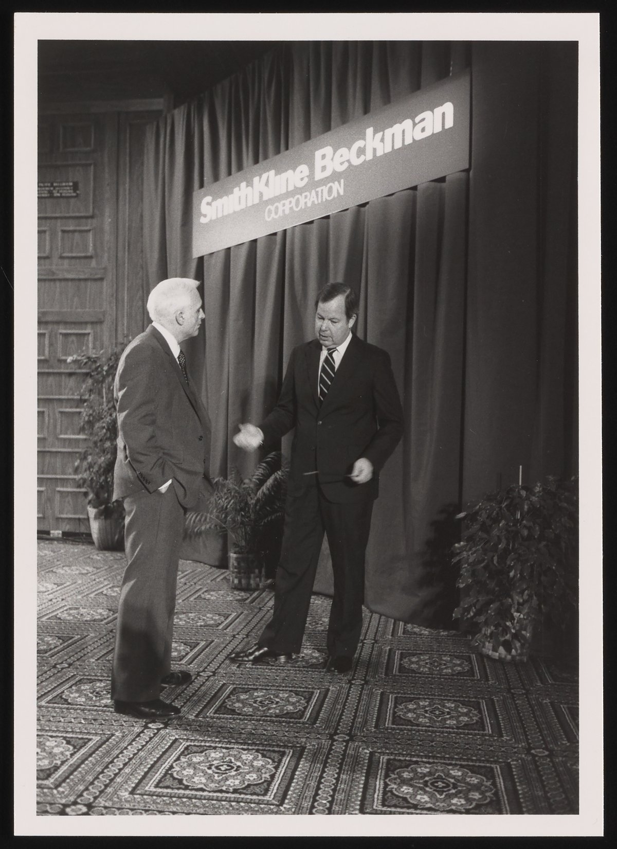 Lou Rosso and unidentified man talking beneath a SmithKline Beckman ...