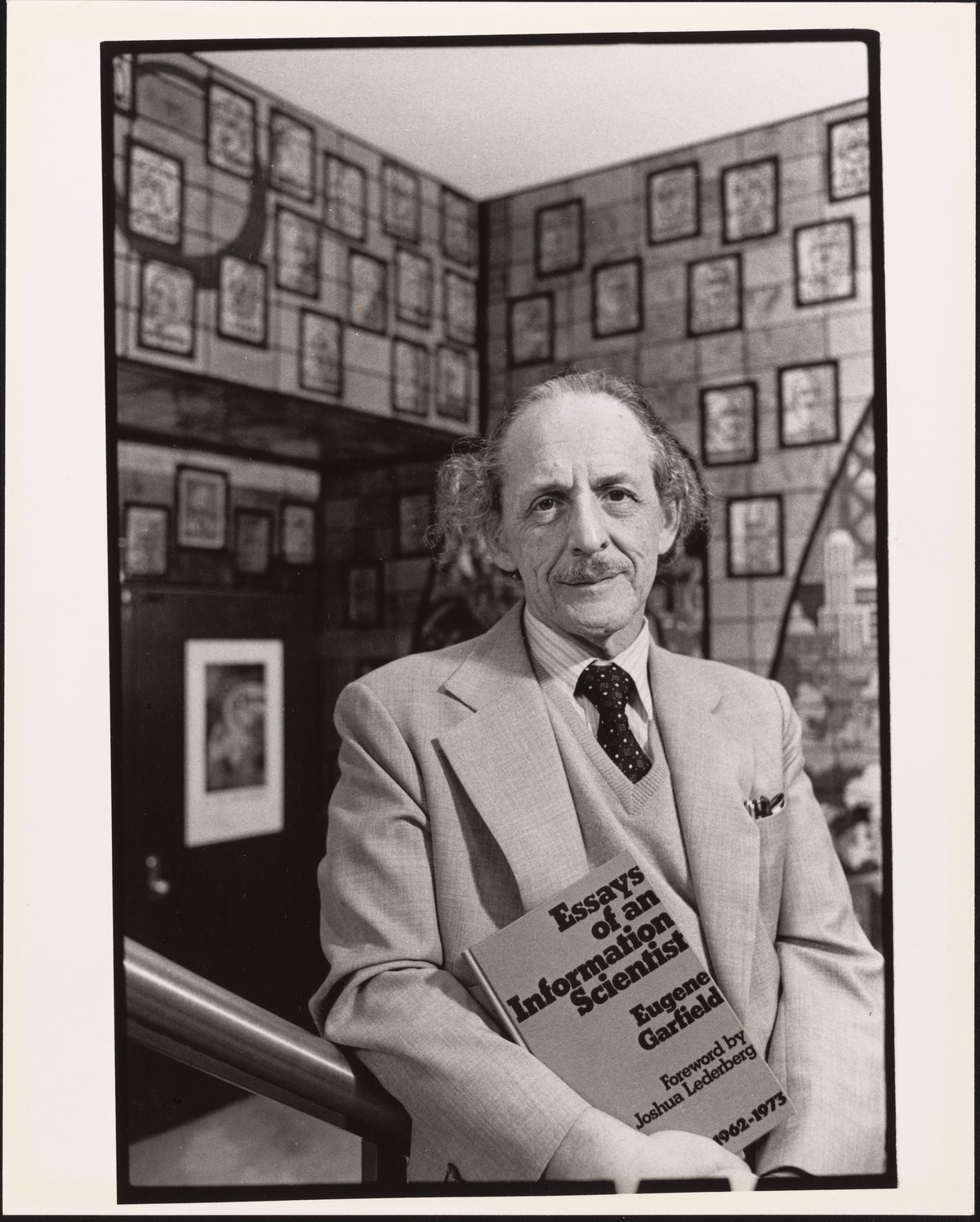 Portrait of Eugene Garfield holding "Essays of an Information Scientist ...